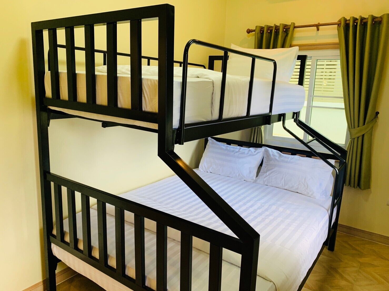 Uma cama beliche com estrutura de metal preta e roupa de cama branca.