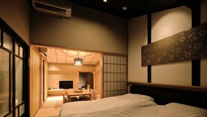 Quarto japonês tradicional com cama, escrivaninha e televisão.
