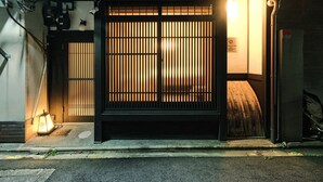 Um portão tradicional japonês com portas deslizantes, uma pequena área de estar ao ar livre e uma placa com a inscrição 'Connect Inn'.