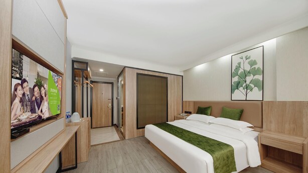 Quarto de hotel moderno com uma cama grande, mesa de cabeceira, televisão e guarda-roupa.