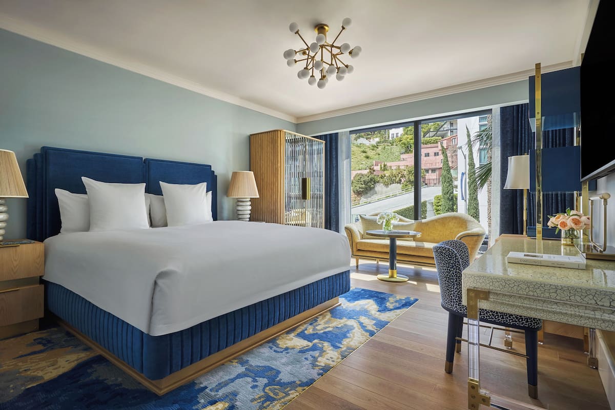 Quarto de hotel com uma cama grande, uma mesa e vista para a cidade.