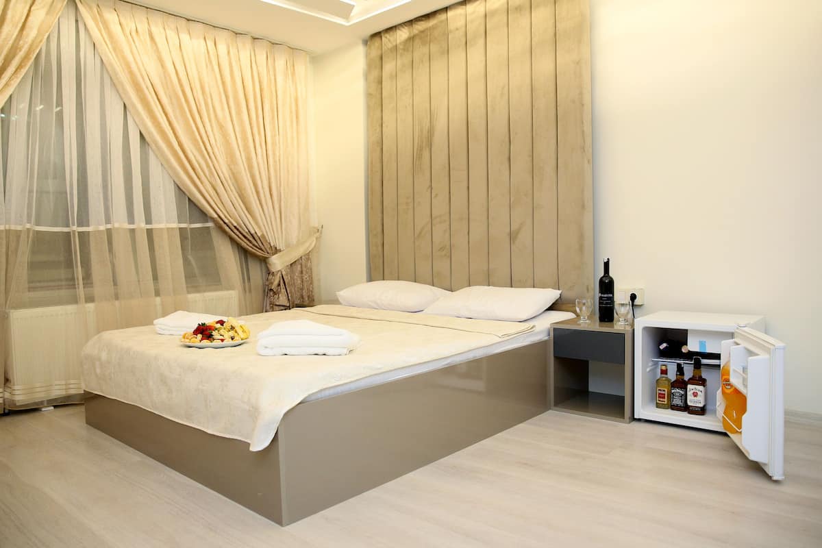 Quarto moderno com cama, mesa de cabeceira e frigobar.