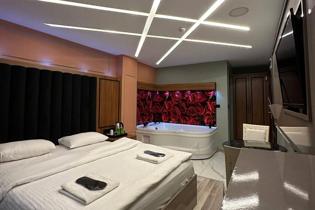 Quarto de hotel moderno com uma cama grande, área de estar separada e uma banheira.