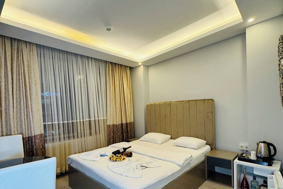 Quarto de hotel moderno com uma cama grande, mesas de cabeceira, uma escrivaninha e uma cadeira.