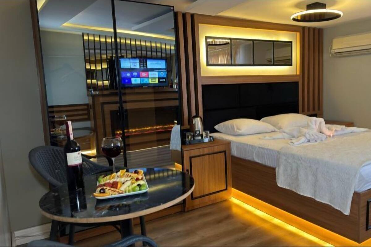 Quarto de hotel com cama, mesa de cabeceira e televisão presa na parede.