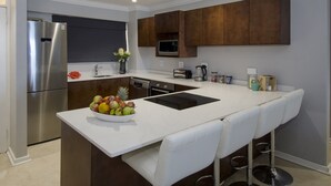 Uma cozinha moderna com eletrodomésticos de aço inoxidável, uma ilha central com banquetas e armários de madeira.