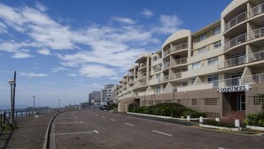 Hotel à beira-mar com várias varandas, um calçadão e vista desobstruída para o mar.