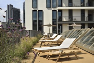 Uma área de lounge no terraço, com espreguiçadeiras, uma mesa e cadeiras.