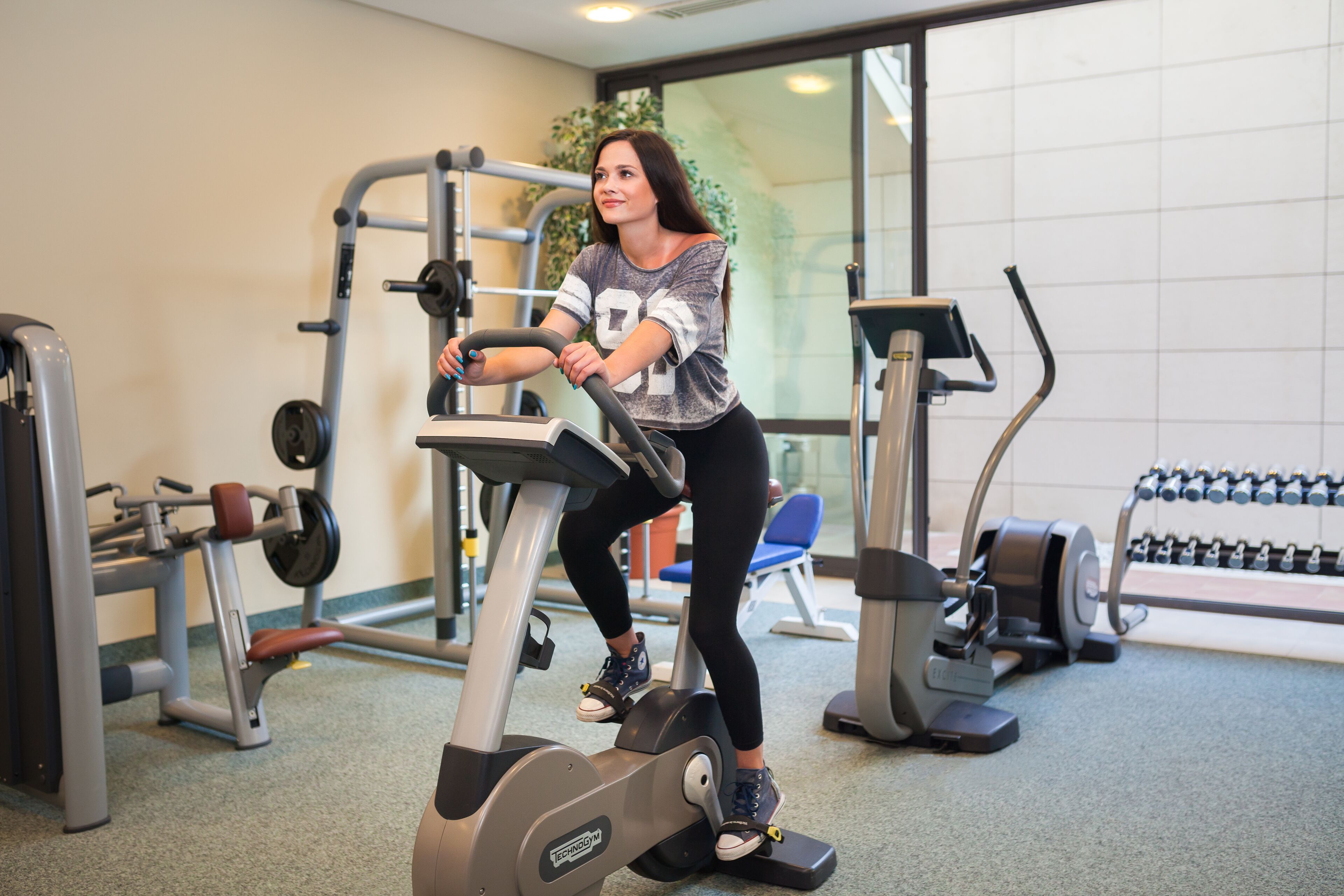 Uma academia com equipamentos de ginástica, incluindo esteira e aparelhos de musculação.