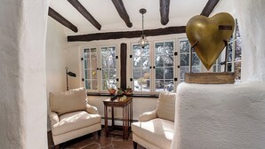 Um quarto aconchegante com duas poltronas bege, uma mesa de madeira e um tapete estampado.