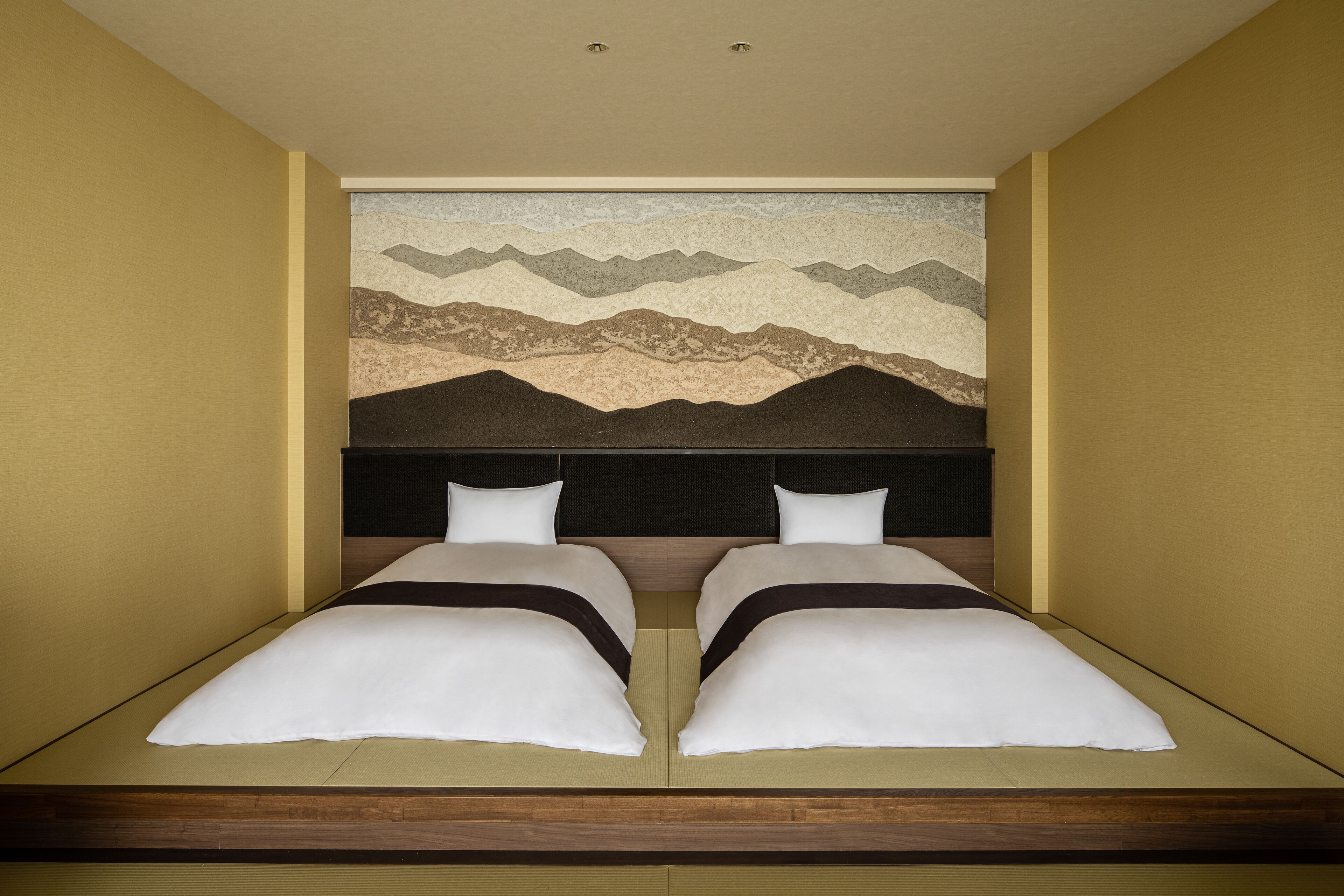 Quarto com duas camas, um grande mural na parede com montanhas e uma cabeceira de madeira.
