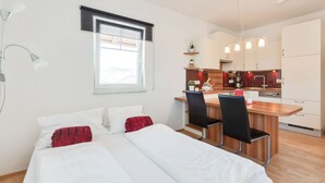 Quarto de hotel moderno com uma cama, uma escrivaninha e uma cozinha compacta.