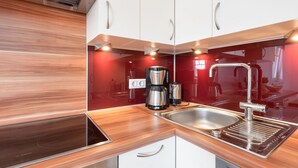 Cozinha moderna com pia de aço inoxidável, cafeteira Bosch e backsplash vermelho.