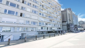 Um hotel com vários andares, design moderno, com varandas em cada pavimento e fachada de vidro destacada.