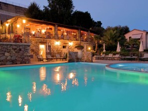 Piscina com espreguiçadeiras e restaurante com área externa.