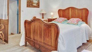 Quarto com cama de madeira, um candelabro, um quadro na parede e uma porta com moldura azul.
