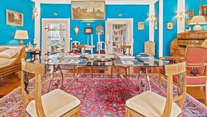 Um quarto com parede azul, uma mesa redonda e um tapete vermelho com padrão.