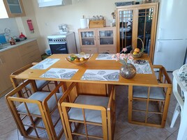 Uma sala de jantar com mesa de madeira, cadeiras e um vaso de flores.