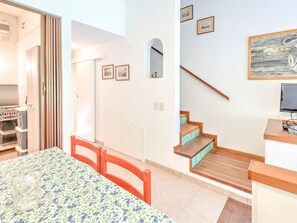 Quarto com cama, escrivaninha, televisão e escada.