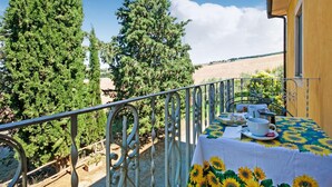 Uma varanda com uma mesa posta para dois, com vista para um campo e árvores.