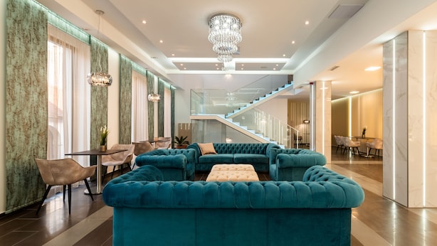 Uma sala de estar espaçosa com um amplo sofá azul-turquesa, um lustre e uma escada que leva a outro nível.