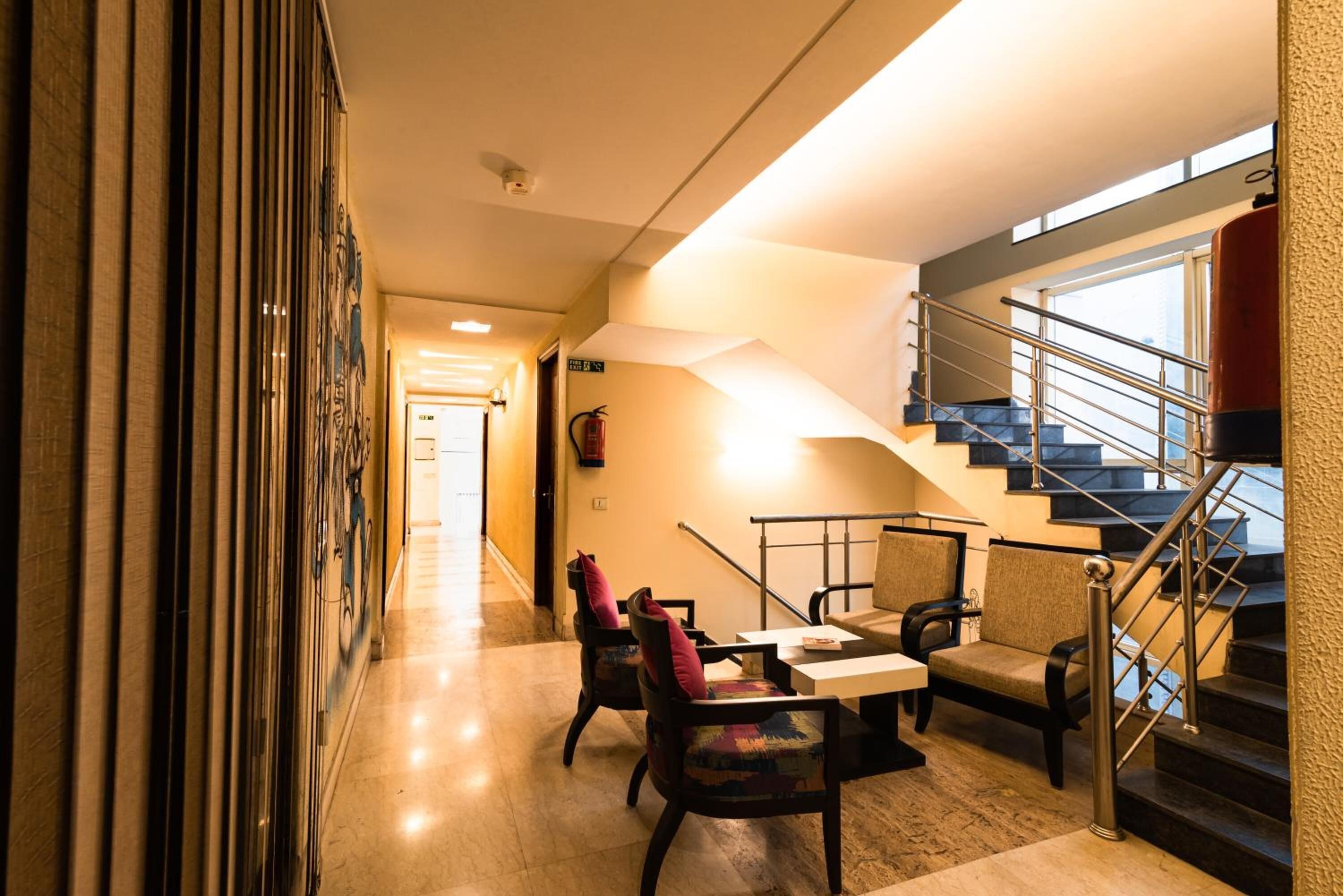 Um hall de hotel com escadas, área de estar e extintor de incêndio.