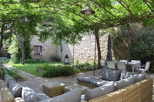 Um pátio com mobiliário de exterior, um muro de pedra e vegetação.