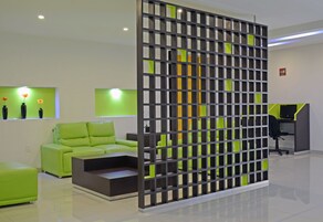 Um interior moderno com um sofá verde, uma divisória preta e uma mesa com um computador.