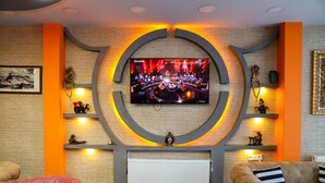 Uma sala de estar moderna com uma grande TV de tela plana fixada em um design de parede circular, lareira e um espaço de estar confortável com sofás e uma mesa de centro.