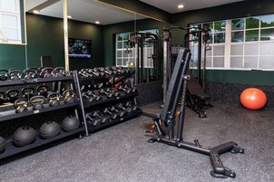 Uma academia com diversos equipamentos de exercícios, incluindo halteres e um banco.