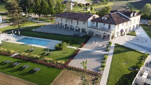 Um grande edifício com piscina, área de estar externa e gramado bem cuidado.