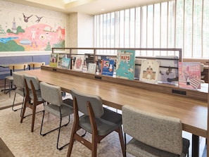 Uma biblioteca com uma mesa comprida, cadeiras e estantes repletas de livros.