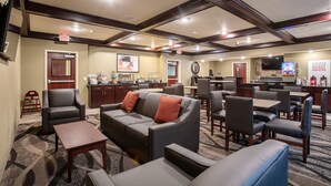 Um saguão de hotel com área de estar, kitchenette e televisão.