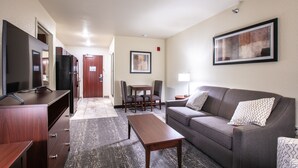 Uma sala de estar moderna com sofá, mesa de centro, televisão e uma área de jantar com cadeiras e mesa.