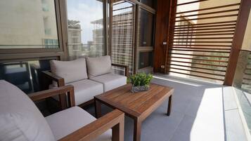 Uma varanda moderna com sofá, mesa de madeira e planta em vaso.