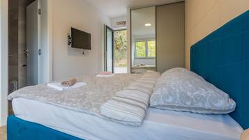 Quarto moderno com uma cama grande, televisão de tela plana e porta de vidro deslizante que dá para uma varanda.