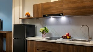 Uma cozinha moderna com armários de madeira, uma geladeira preta, bancada de mármore, pia e um vaso com flores.