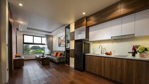 Uma cozinha moderna com armários de madeira, forno embutido e uma janela ampla com vista para o verde.