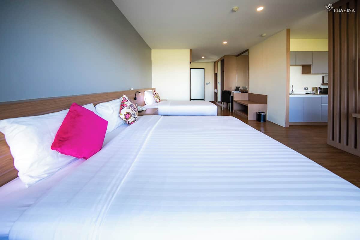 Quarto de hotel com duas camas, cozinha compacta e banheiro.