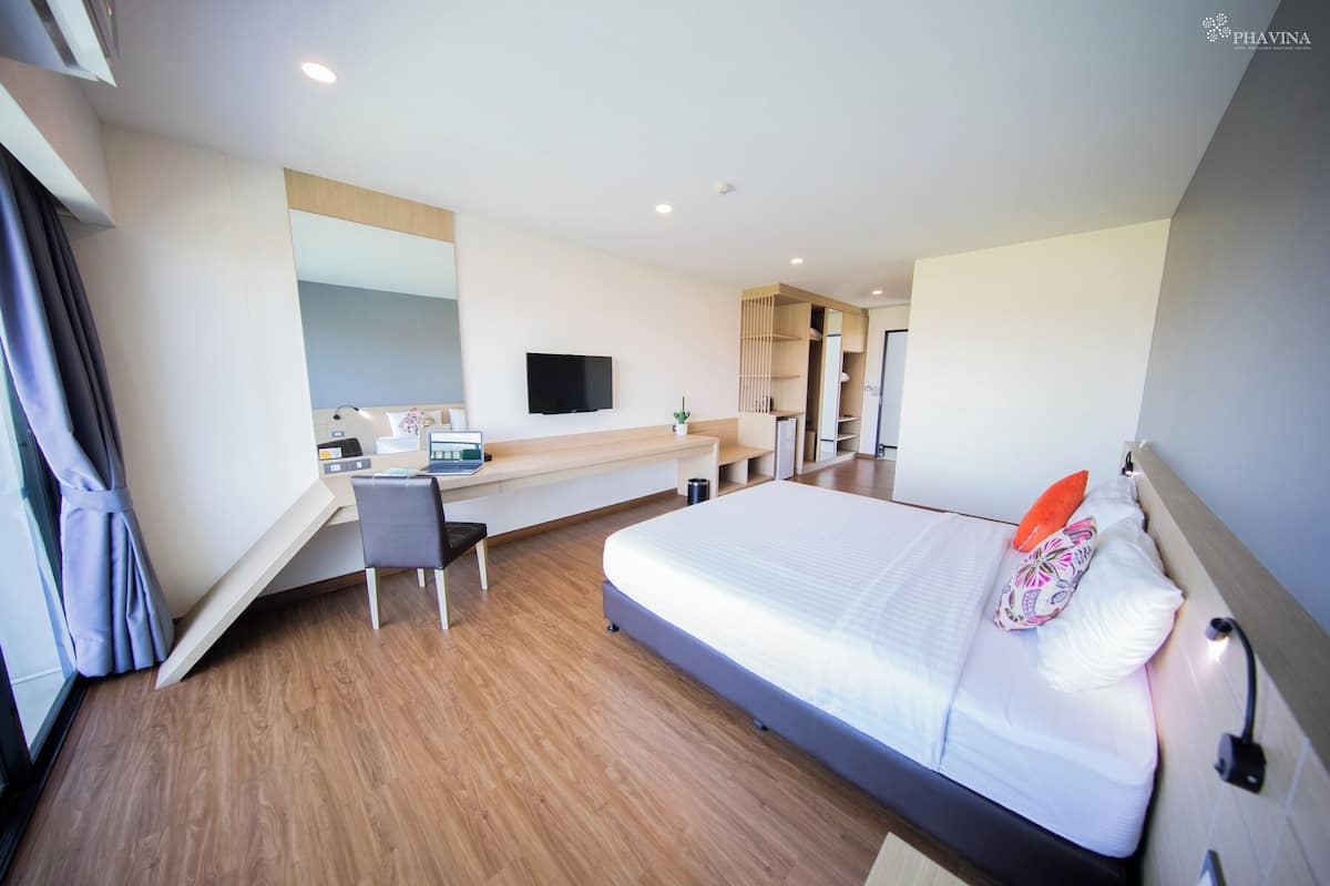 Quarto de hotel moderno com cama, escrivaninha, cadeira e televisão de tela plana.