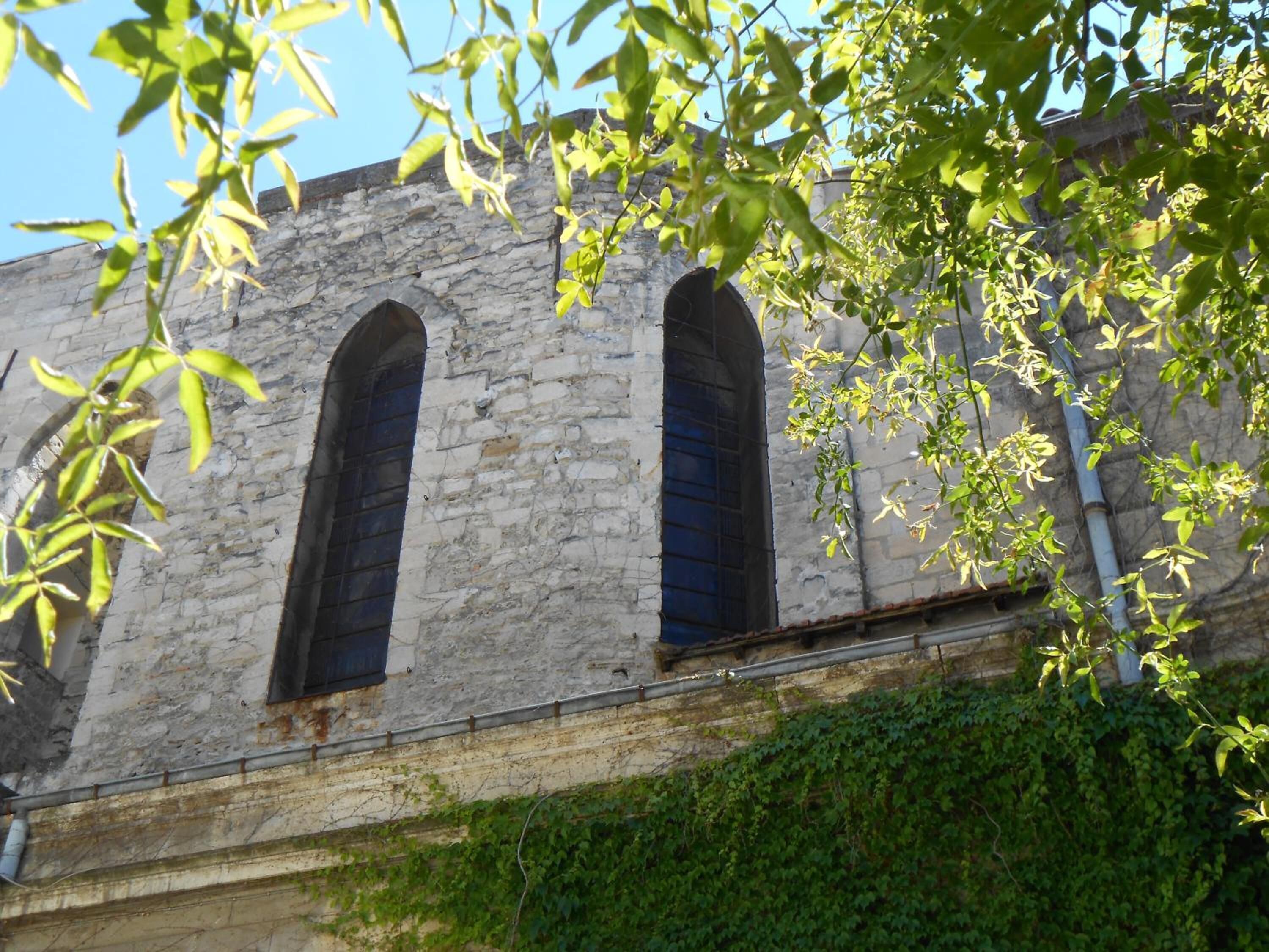 Edifício de pedra com duas janelas em arco e guarda-corpo de metal.