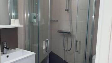 Uma casa de banho moderna com cabine de duche em vidro, lavatório branco e sanita.