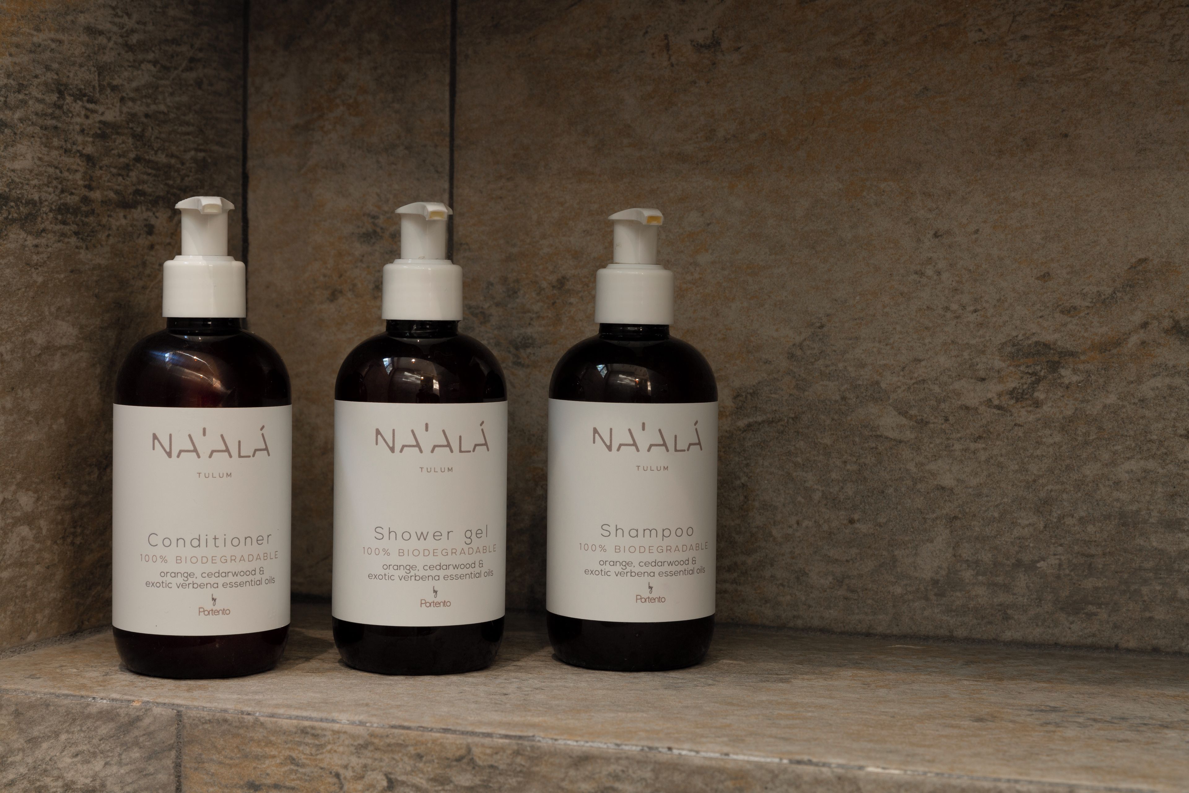 Três frascos de produtos de banho N'ALÁ sobre um degrau de pedra.