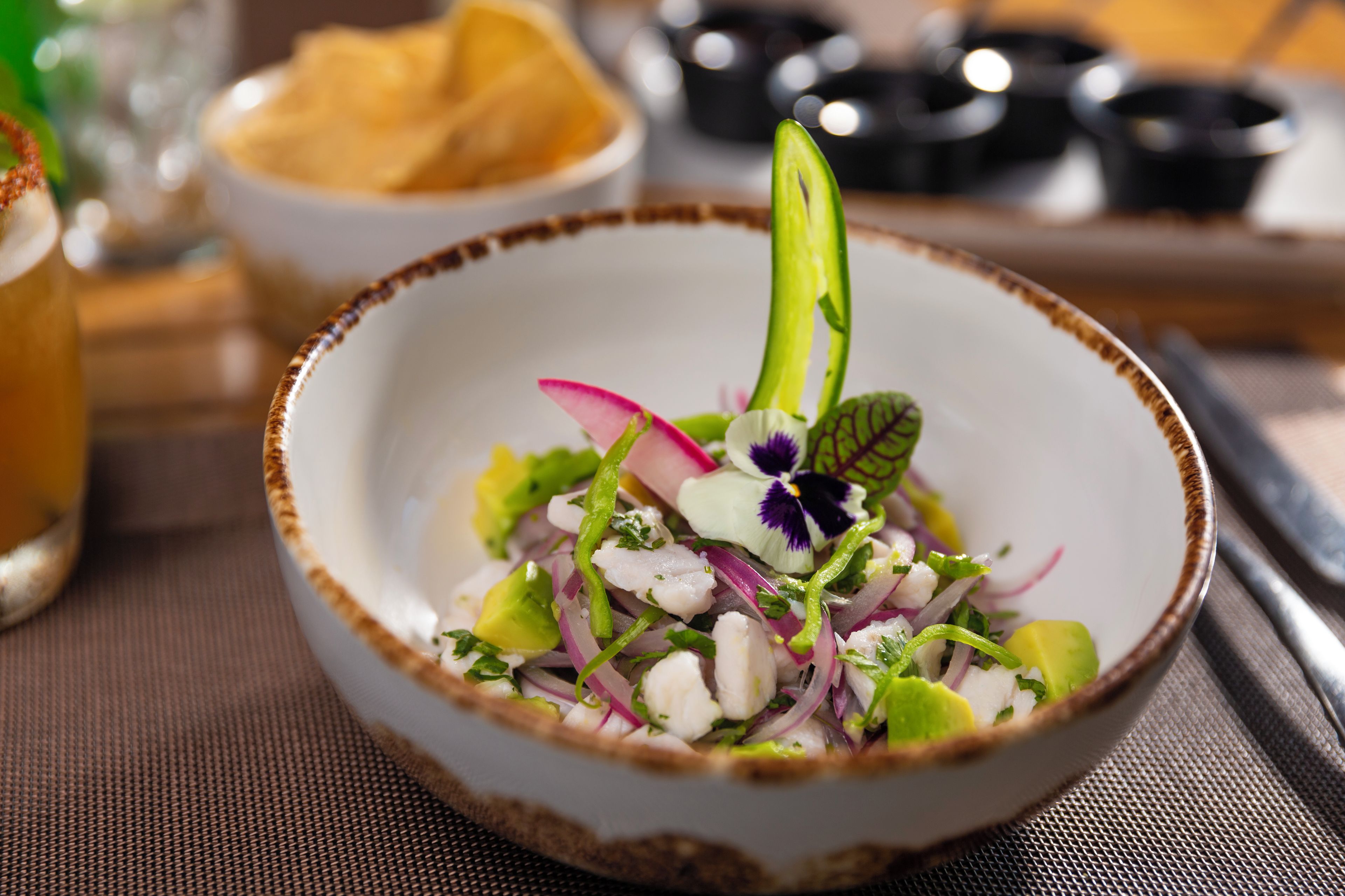 Uma salada em uma tigela, com diversos ingredientes e uma flor decorativa por cima.