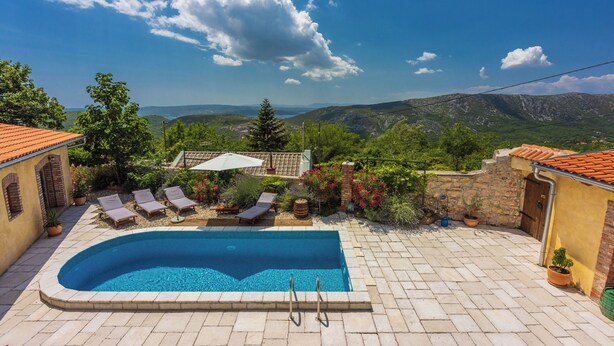 Piscina com espreguiçadeiras e vista para montanhas.
