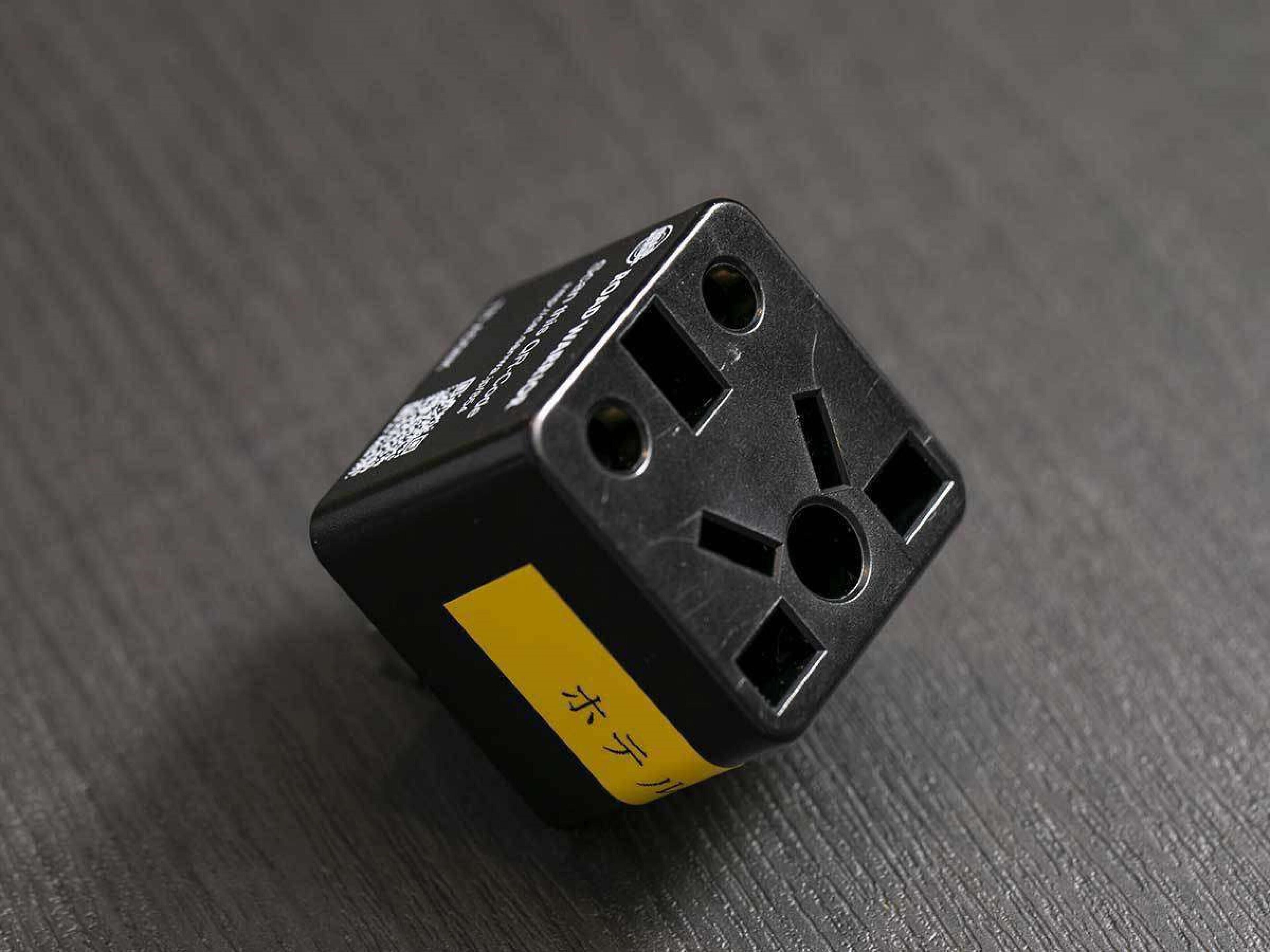 Um dispositivo eletrônico preto com uma etiqueta amarela sobre uma superfície escura.