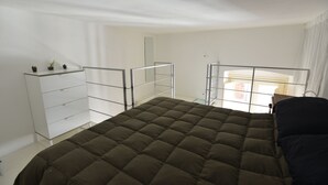 Um quarto com cama, cômoda e janela com cortinas.