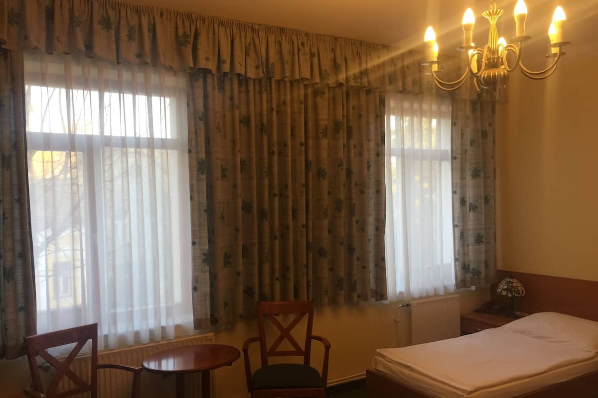 Quarto de hotel com cama, cadeira, mesa e lustre.