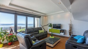 Uma sala de estar moderna com uma janela grande, um sofá, uma mesa de centro e uma televisão.
