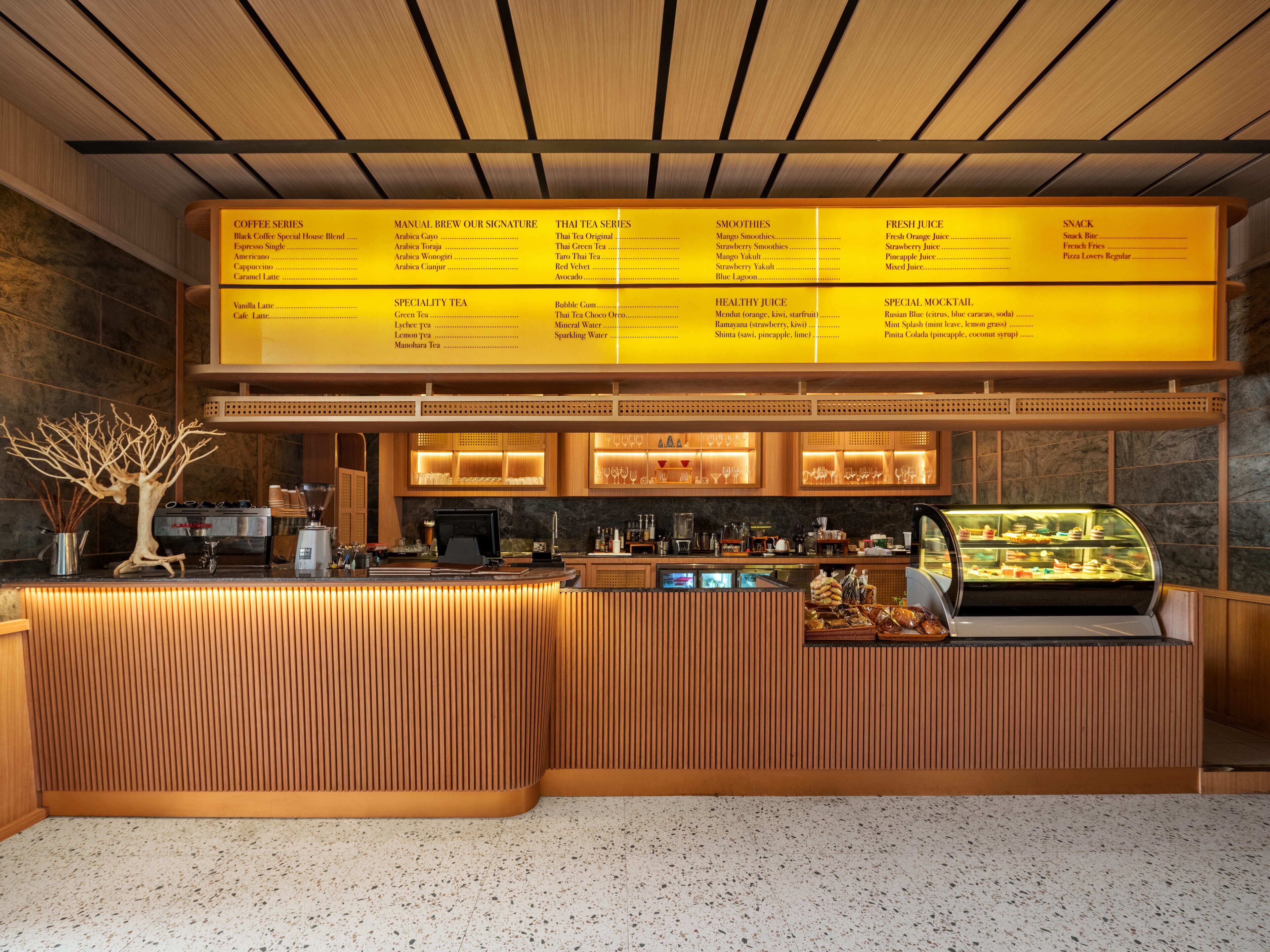 Uma área de bar moderna com um quadro de menu exibindo café, chá, smoothies, suco fresco e lanches.